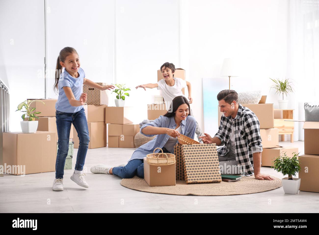 Happy family unpacking moving boxes at their new home Stock Photo - Alamy