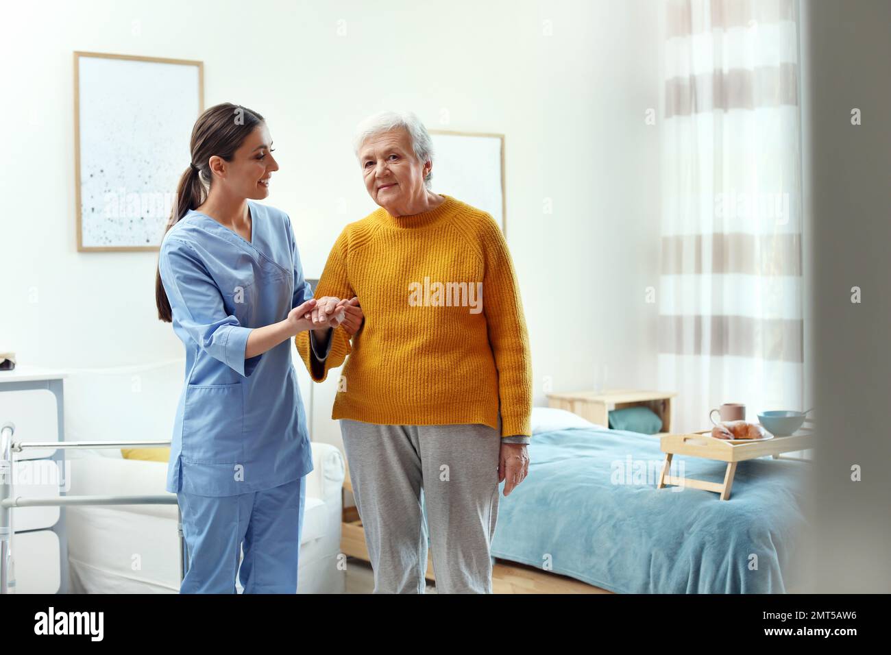 Care worker helping elderly woman to walk in geriatric hospice Stock ...