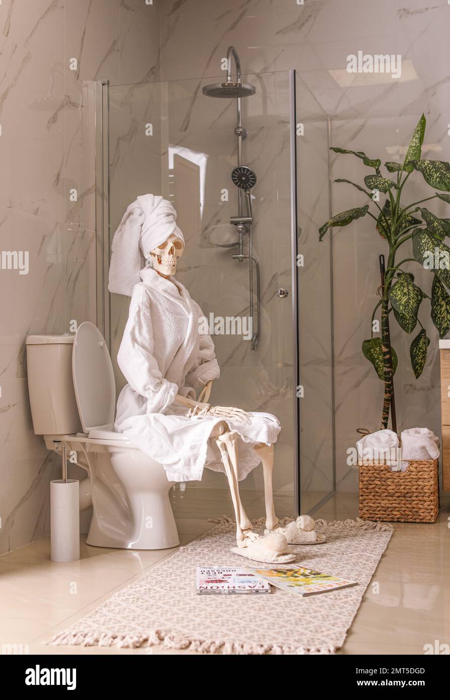 Skeleton in bathrobe sitting on toilet bowl Stock Photo - Alamy