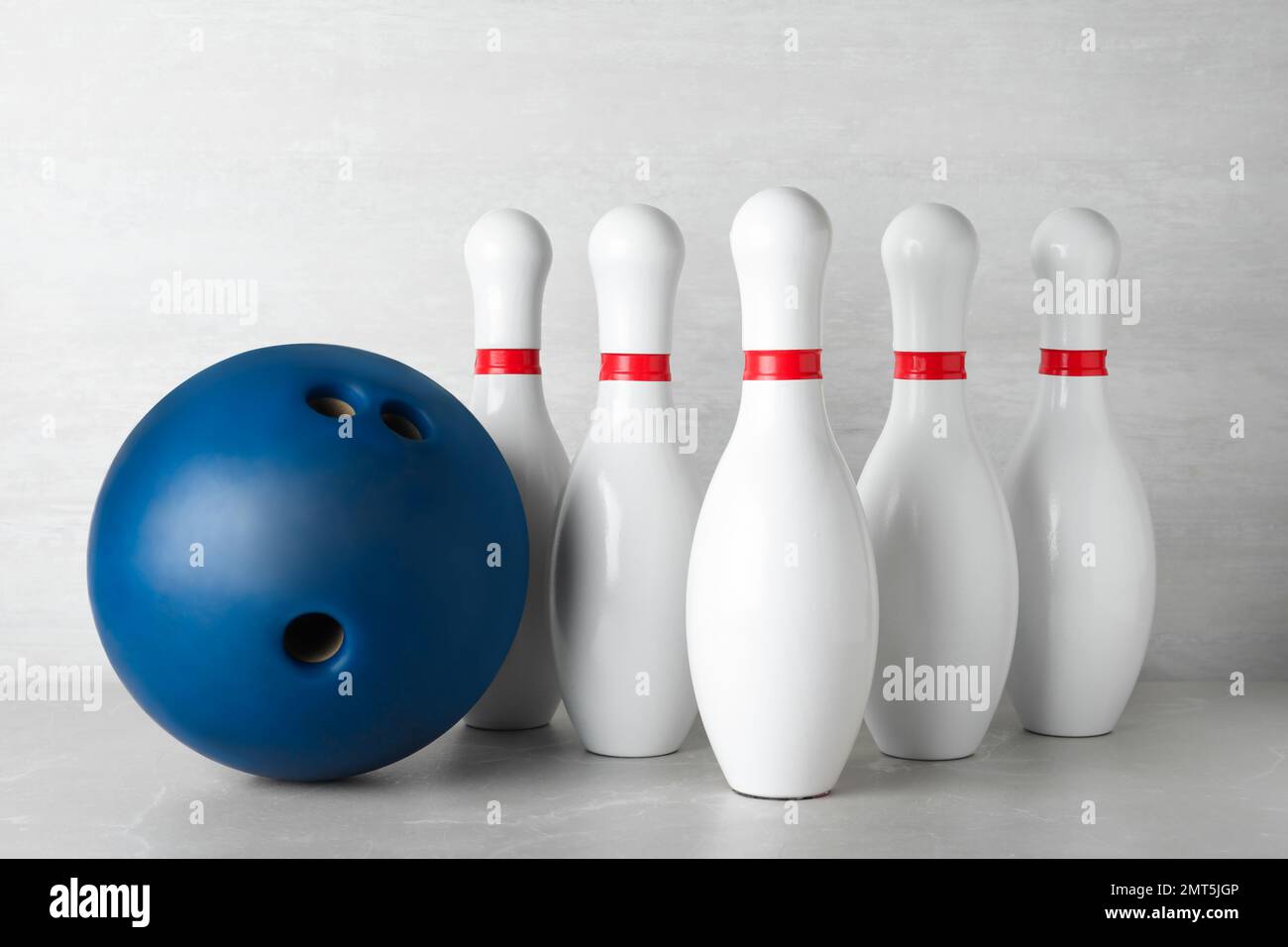 Blue bowling ball and pins on light grey marble table Stock Photo - Alamy