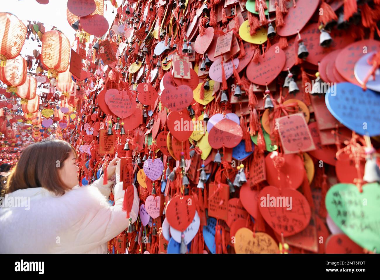 A wishing wall covered with various wishing cards attracts people in a ...