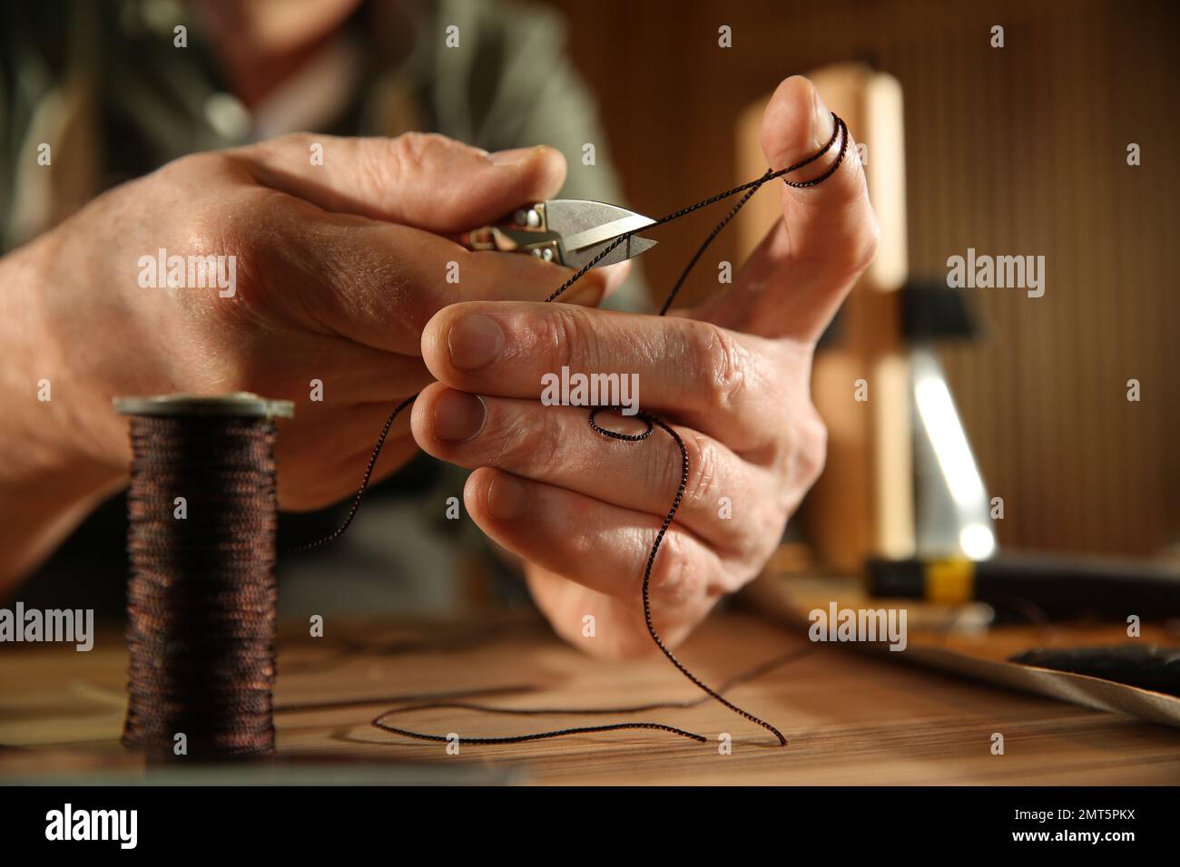 Man cutting thread while working with leather at table, closeup Stock ...