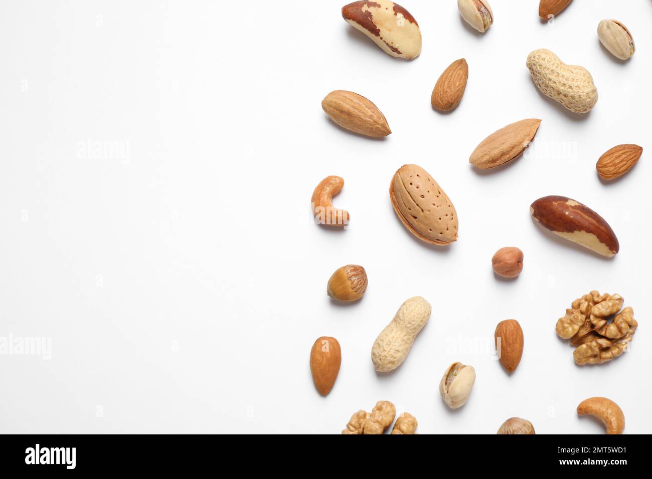 Different delicious nuts on white background, flat lay. Space for text ...