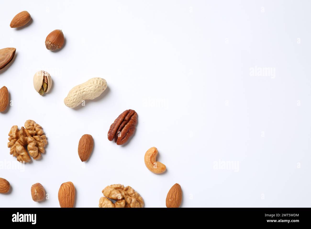 Different delicious nuts on white background, flat lay. Space for text ...