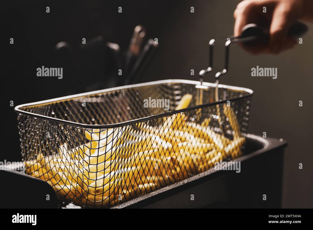 Chef cooking delicious french fries in hot oil, closeup Stock Photo - Alamy
