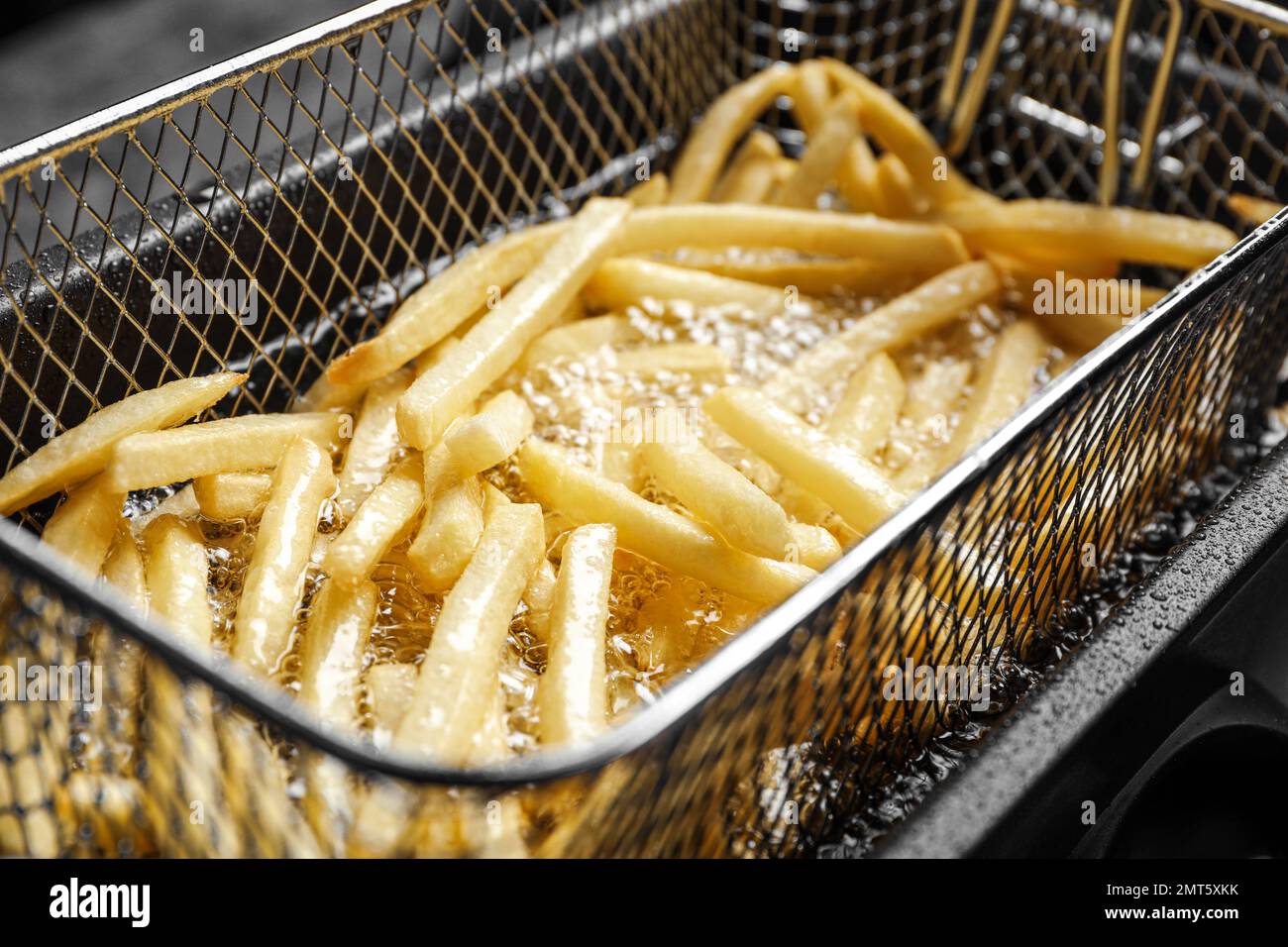 Cooking delicious french fries in hot oil, closeup Stock Photo - Alamy