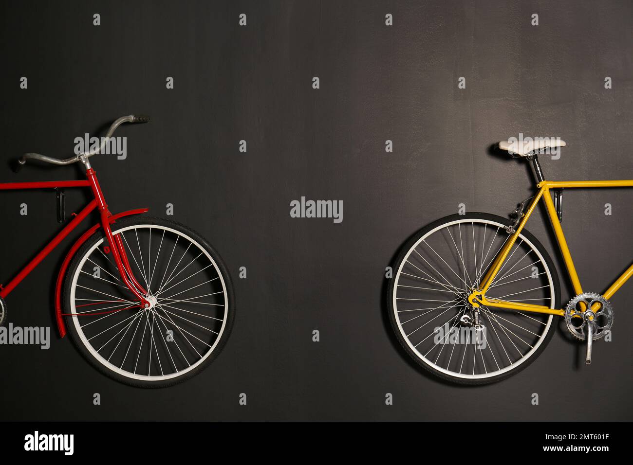 Color bicycles hanging on black wall indoors Stock Photo - Alamy