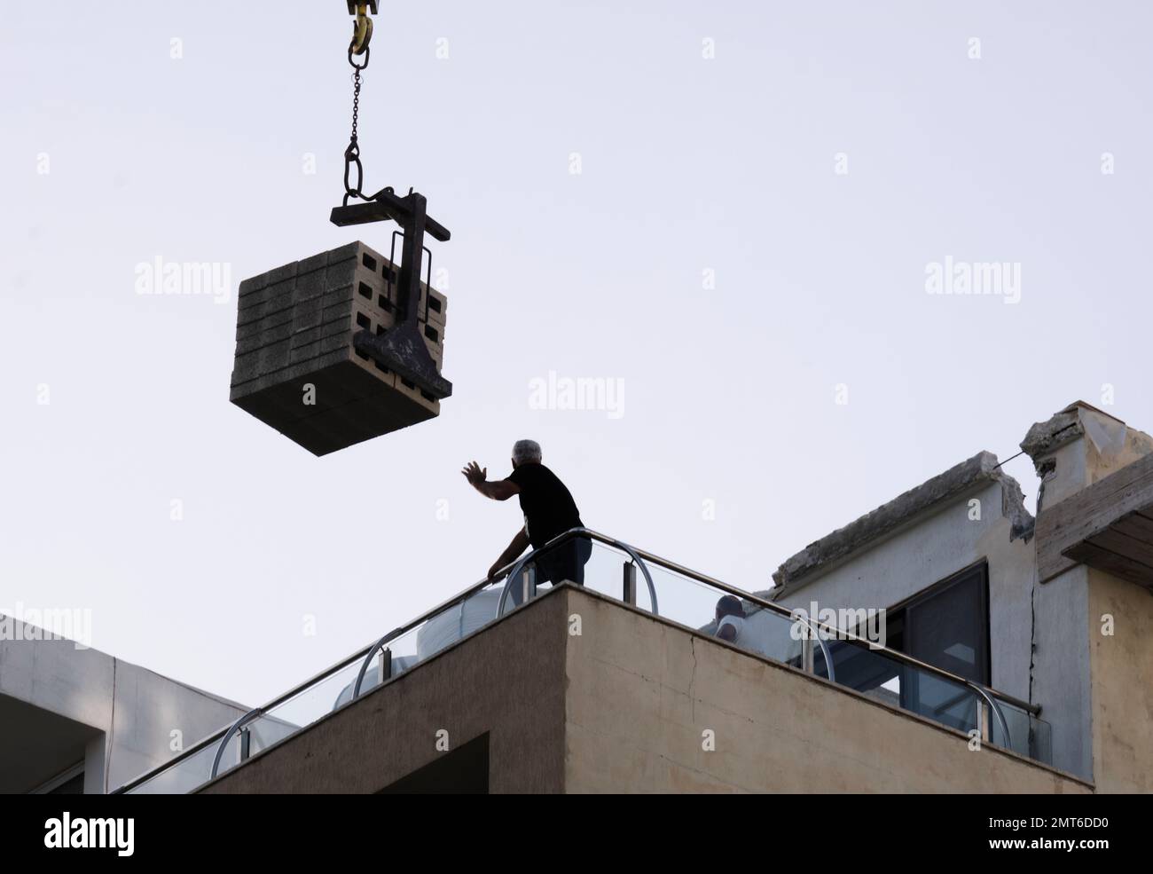 a worker on top of a building coordinating the unloading of building ...