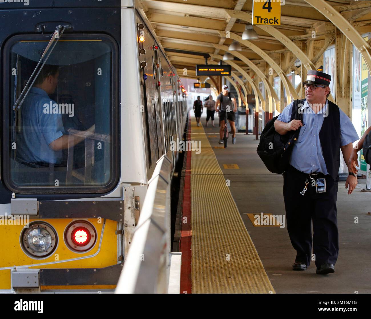 A Long Island Rail Road conductor, right,walks along the platform at ...