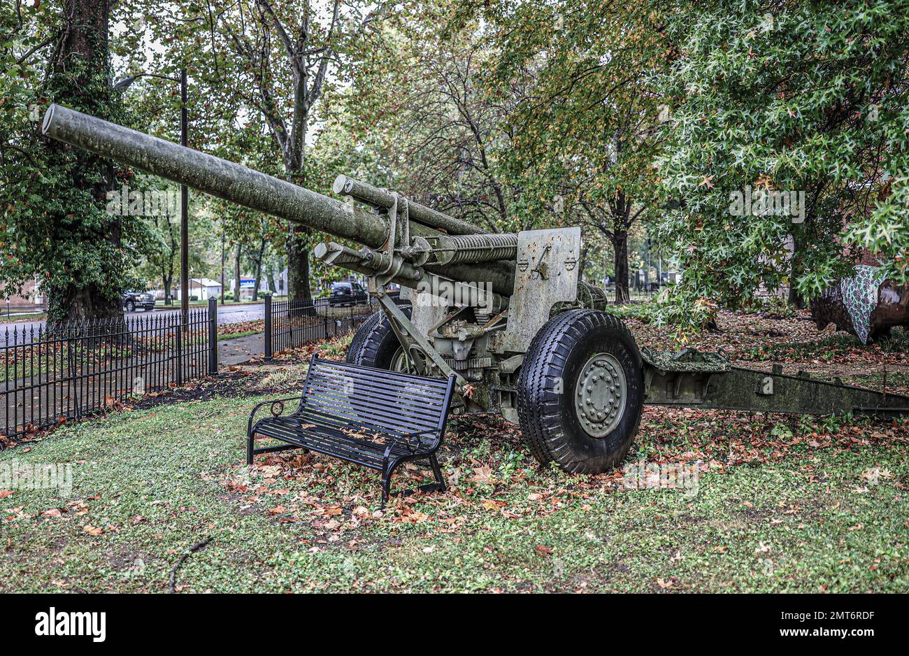A historical cannon displayed in a green park next to a bench Stock ...