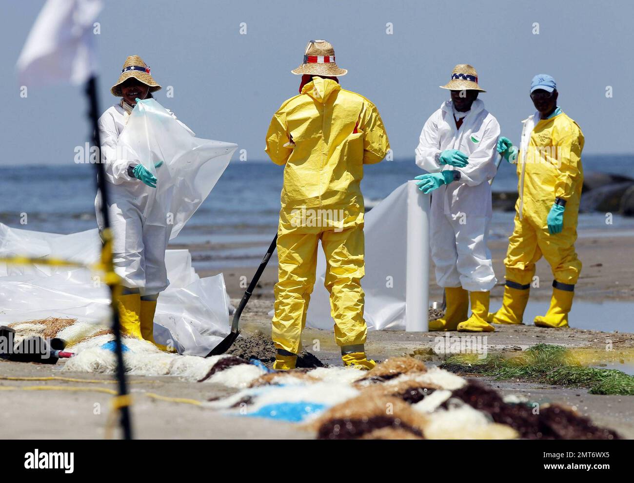 Workers clean up contaminated parts of the beach to remove oil in Grand ...