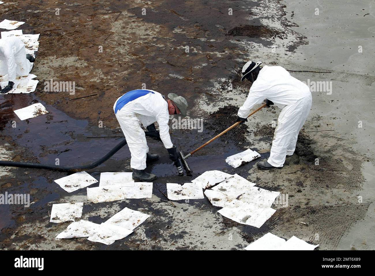 Workers clean oil from the beaches that washed ashore from the oil leak ...