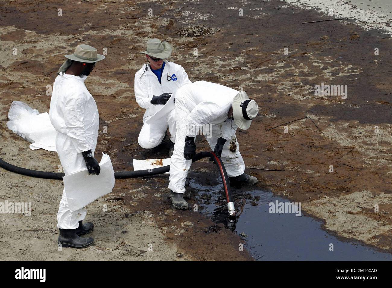 Workers clean oil from the beaches that washed ashore from the oil leak ...