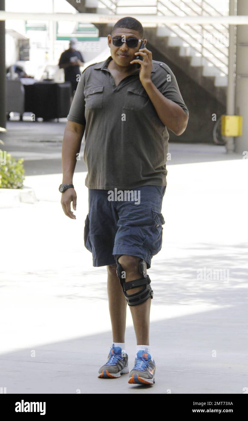 Wearing a knee brace, actor Omar Benson Miller chats on his cellphone ...