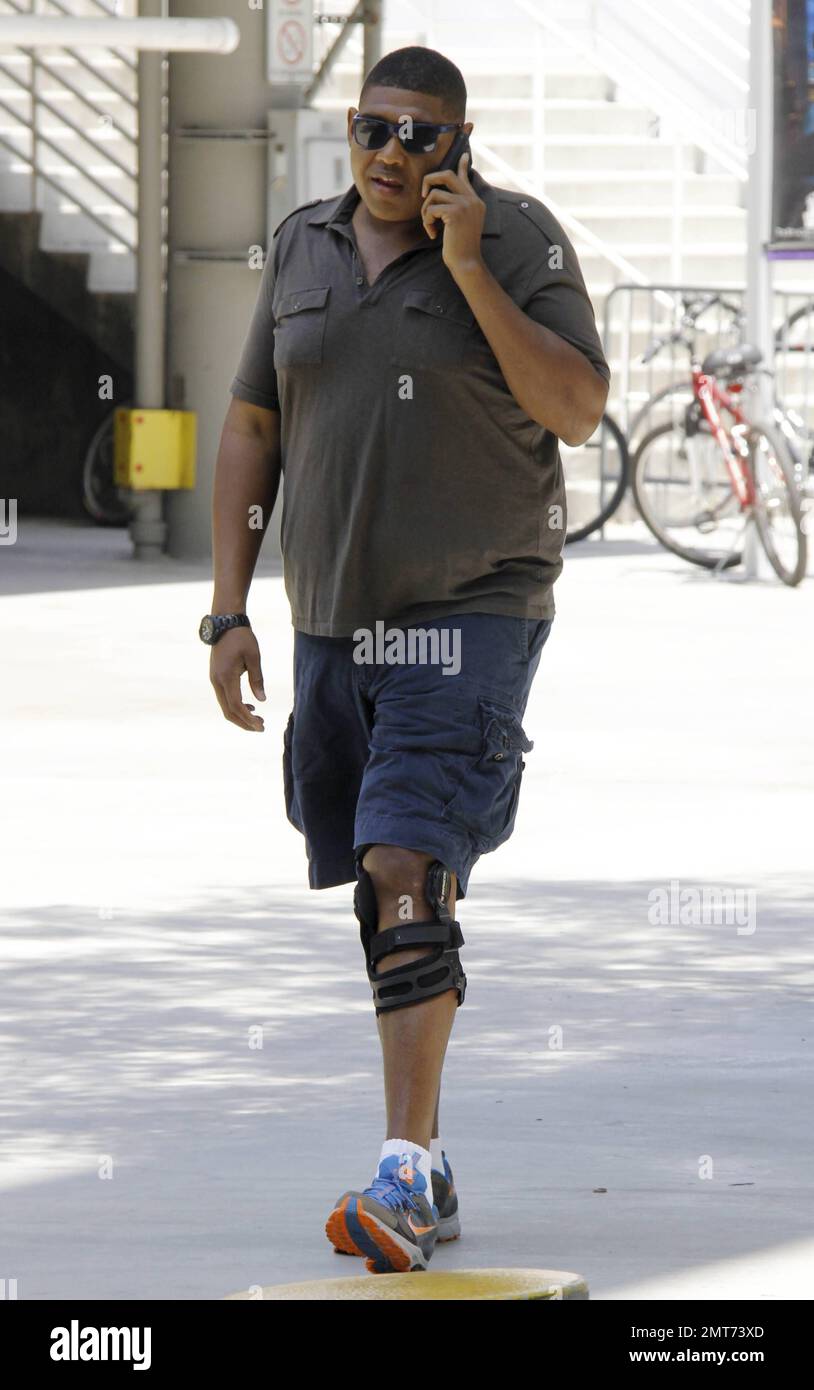 Wearing a knee brace, actor Omar Benson Miller chats on his cellphone ...