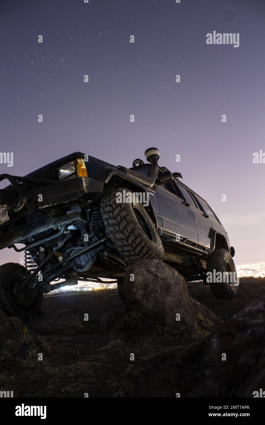 A vertical shot of a 4x4 off-road car on rocky ground at night Stock ...