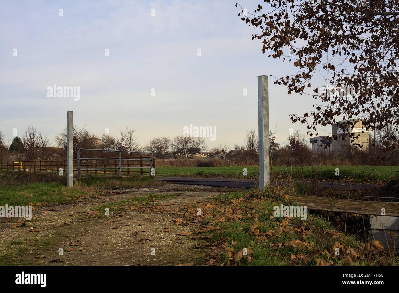 Crossing between a dirt path and a paved one marked by two poles and a ...