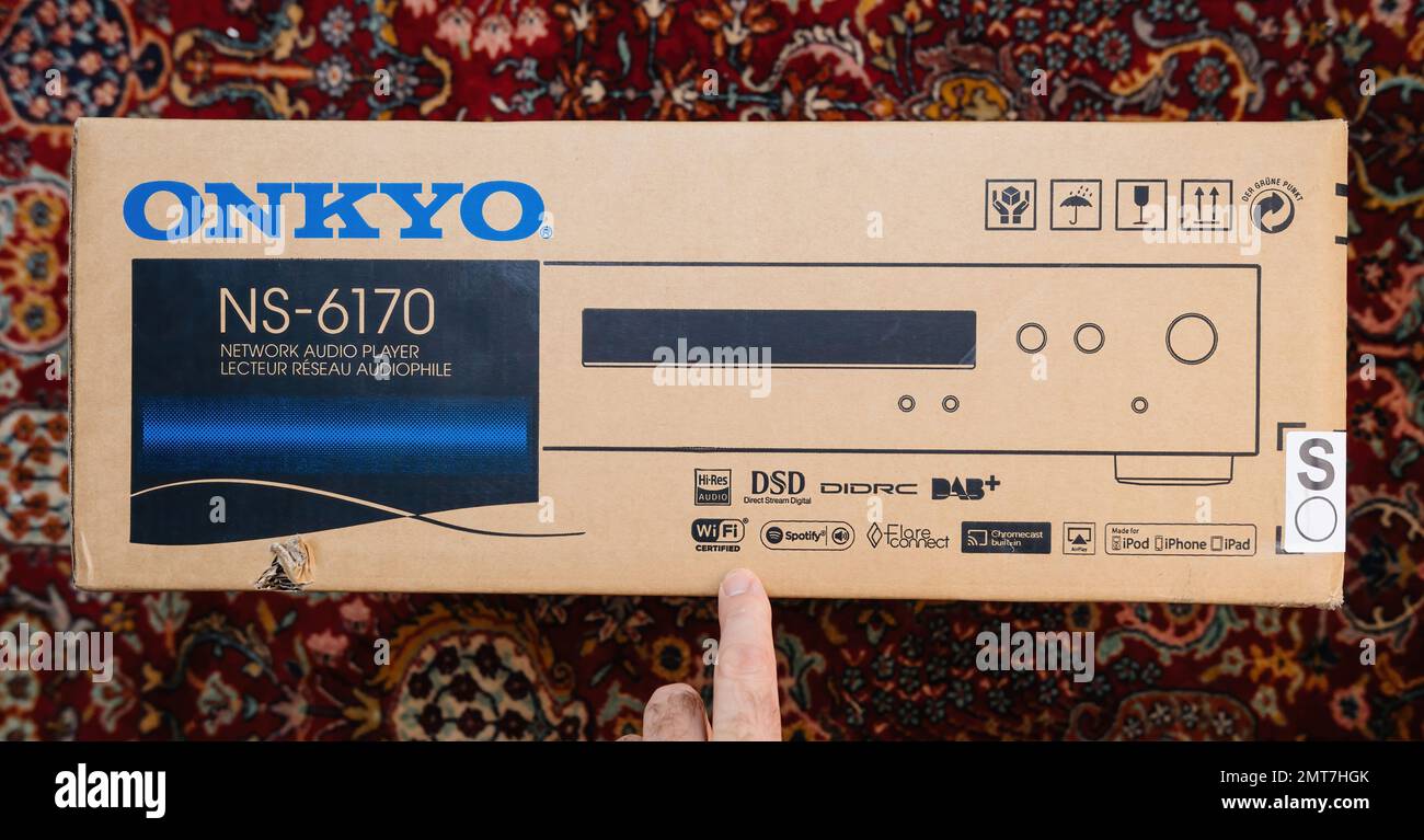 Paris, France - Dec 13, 2022: POV male hand pointing to cardboard package of new Onkyo NS-6170 ...