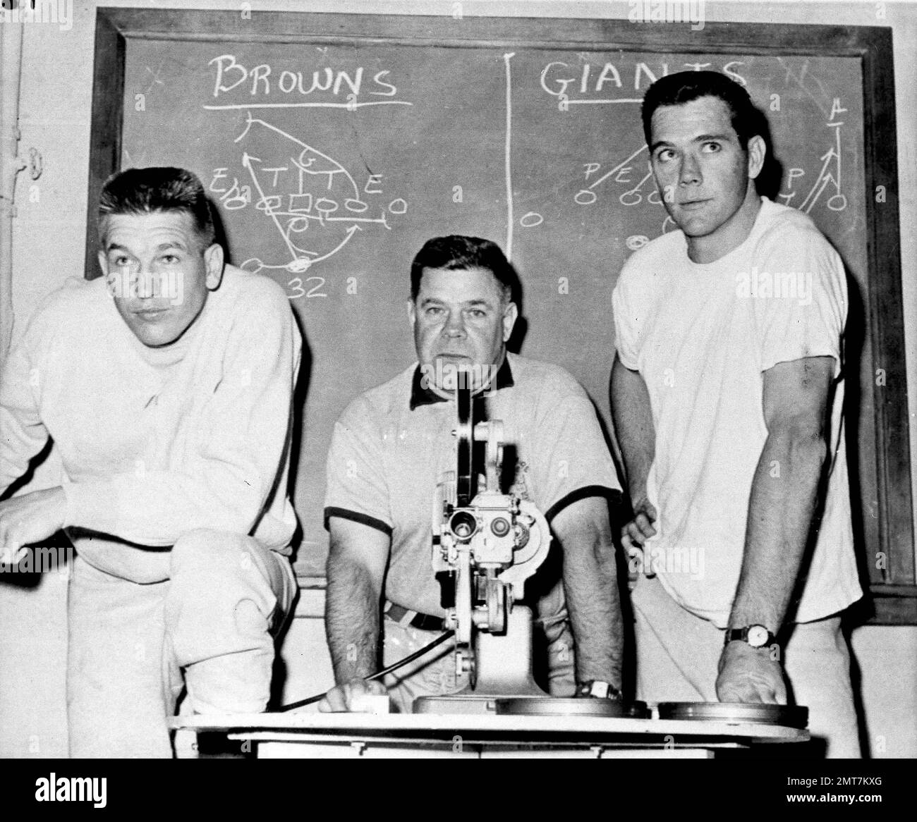 Diagrams on the blackboard tell the story as coach Weeb Ewbank, center ...