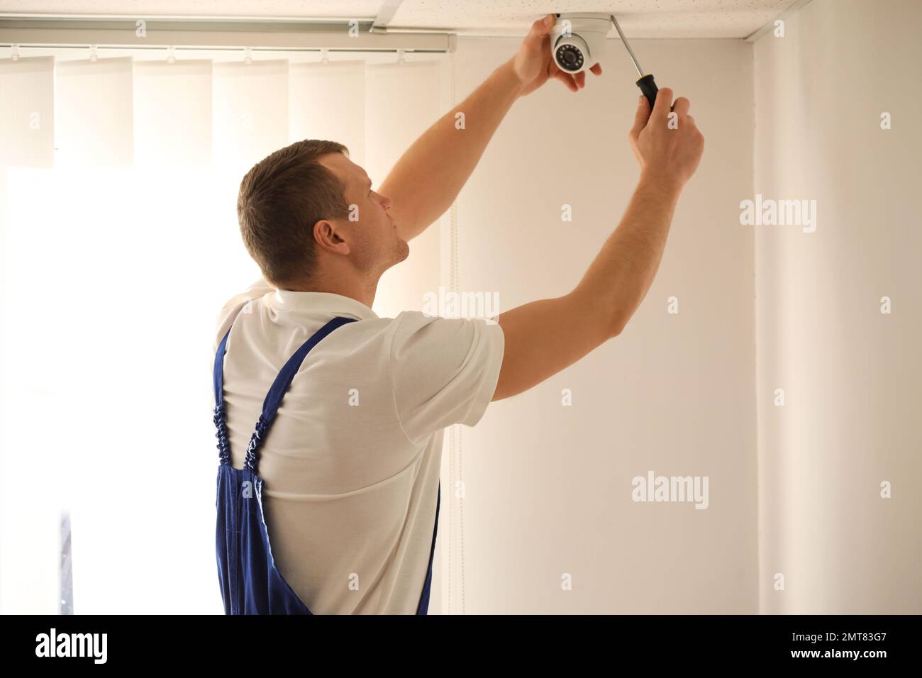 Technician installing CCTV camera on ceiling indoors Stock Photo - Alamy