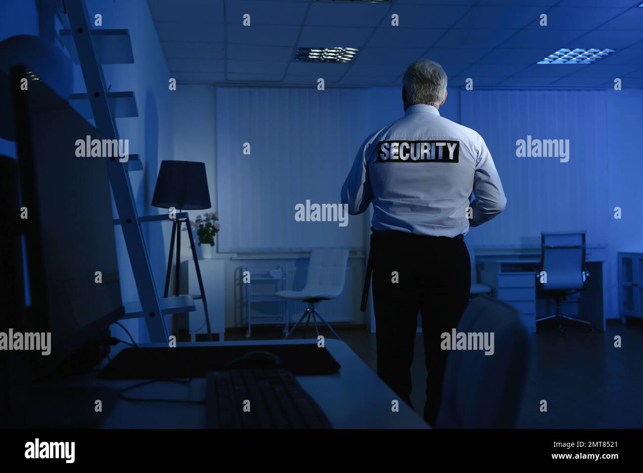 Professional security guard at work in dark office Stock Photo - Alamy