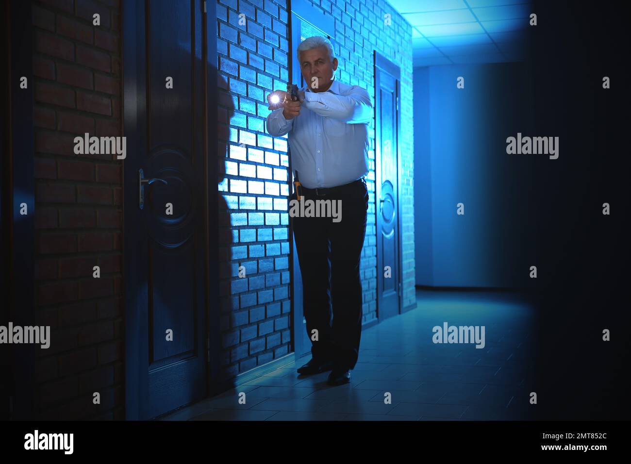 Professional security guard with gun and flashlight checking dark ...