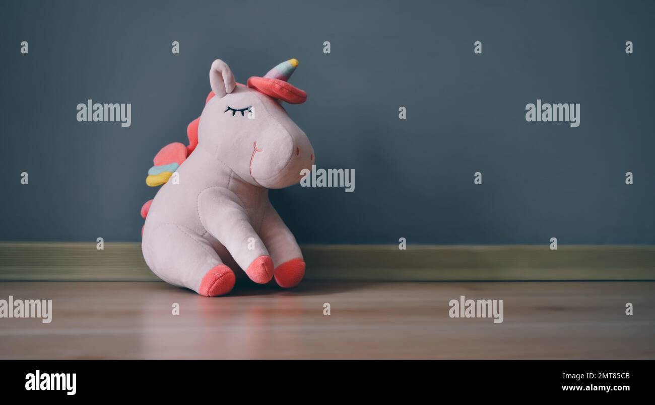 Cute soft unicorn plush toy on the floor. Close up shot, empty space ...