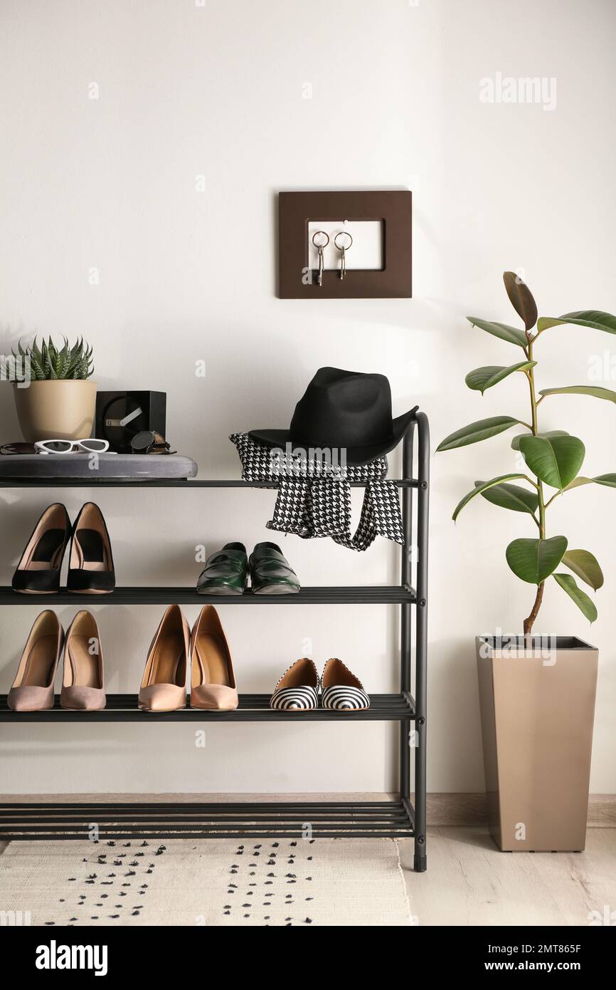 Black shelving unit with shoes and different accessories near white ...