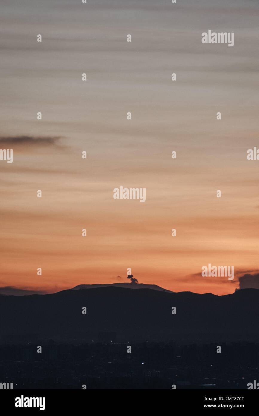 A vertical shot of mountain silhouettes with the background of sunset ...