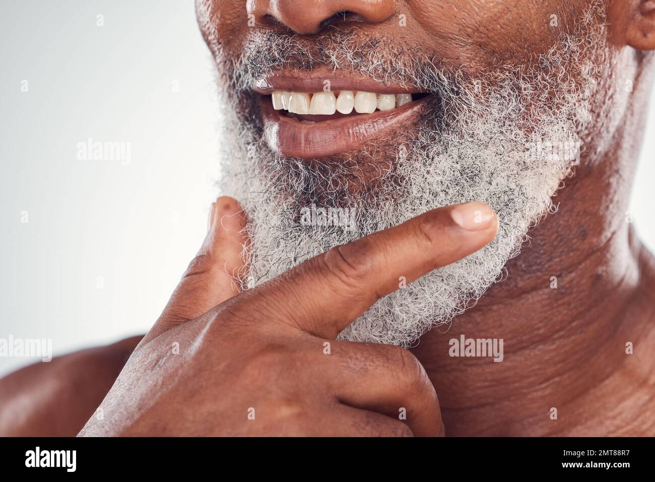Hand, beard and smile with a senior black man grooming in studio on a ...