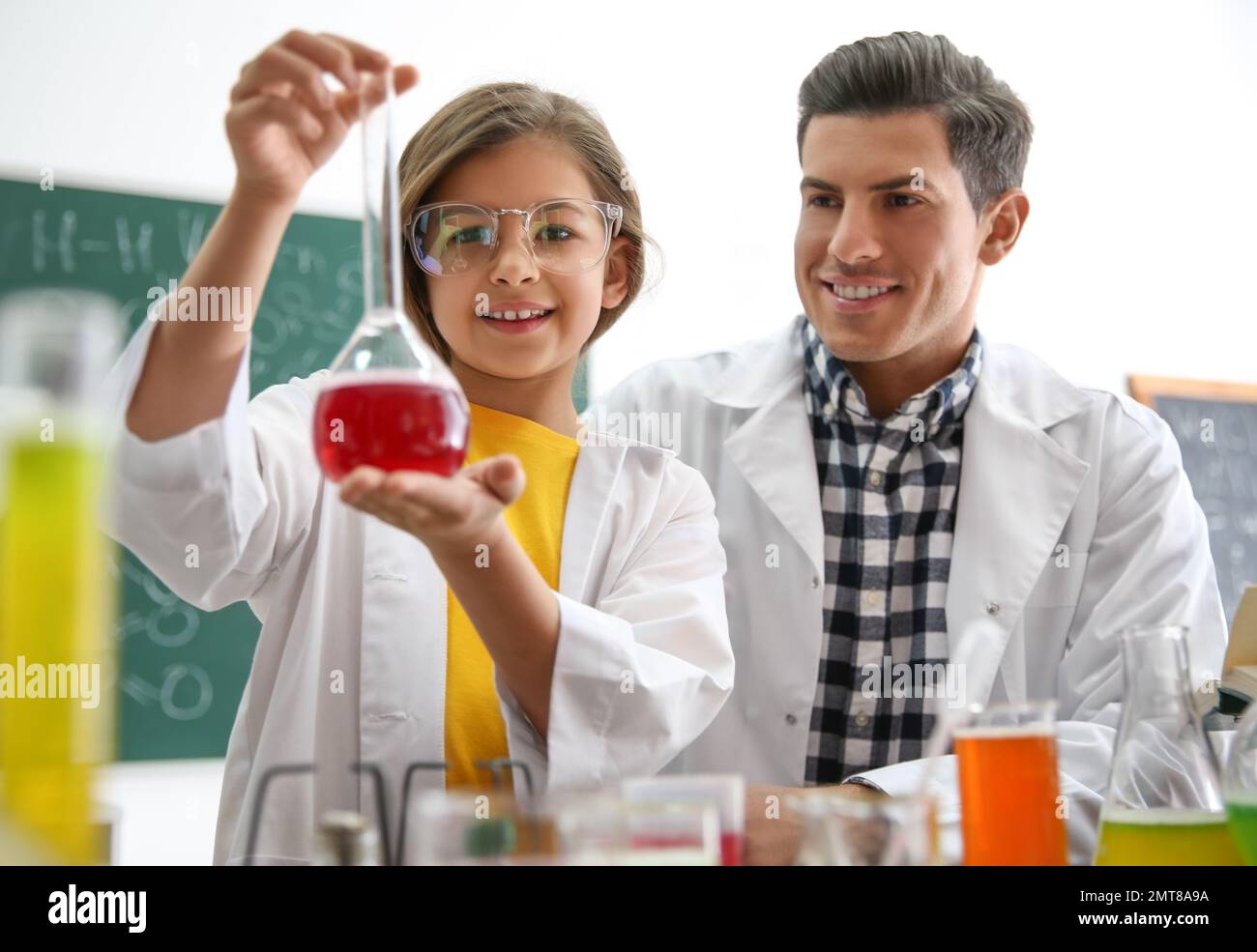 Teacher with pupil making experiment in chemistry class Stock Photo - Alamy