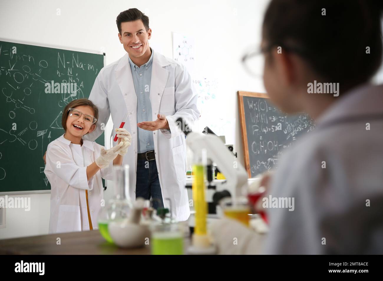Teacher with pupil at chemistry lesson in classroom Stock Photo - Alamy