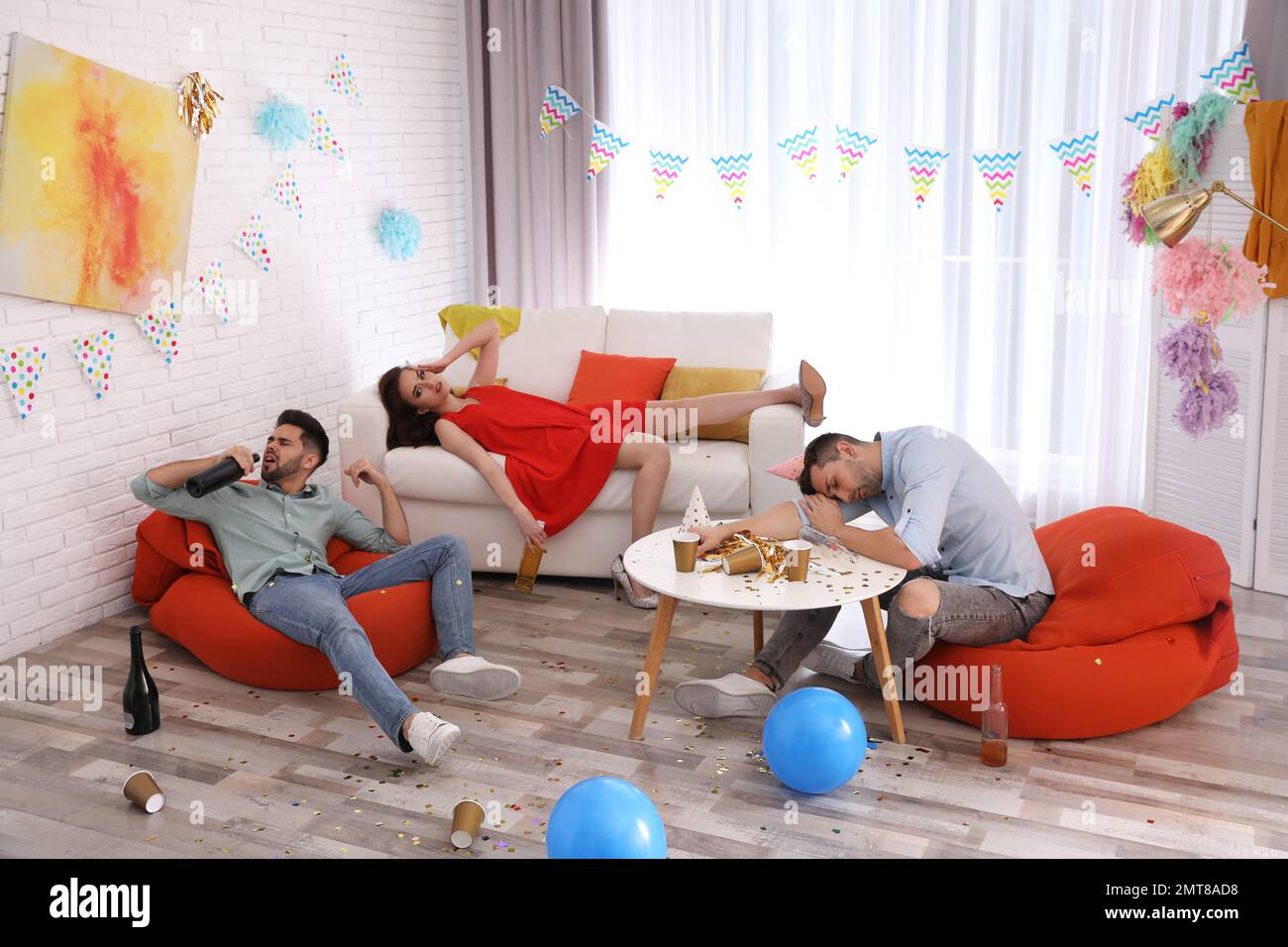 Friends suffering from hangover in messy room after party Stock Photo ...