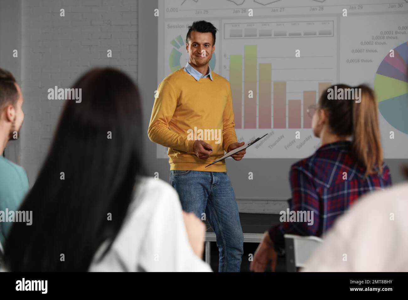 Male business trainer giving lecture in conference room with projection ...