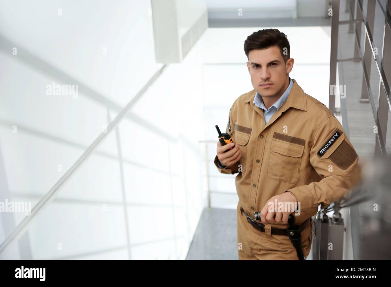 Professional security guard with portable radio set on stairs. Space ...