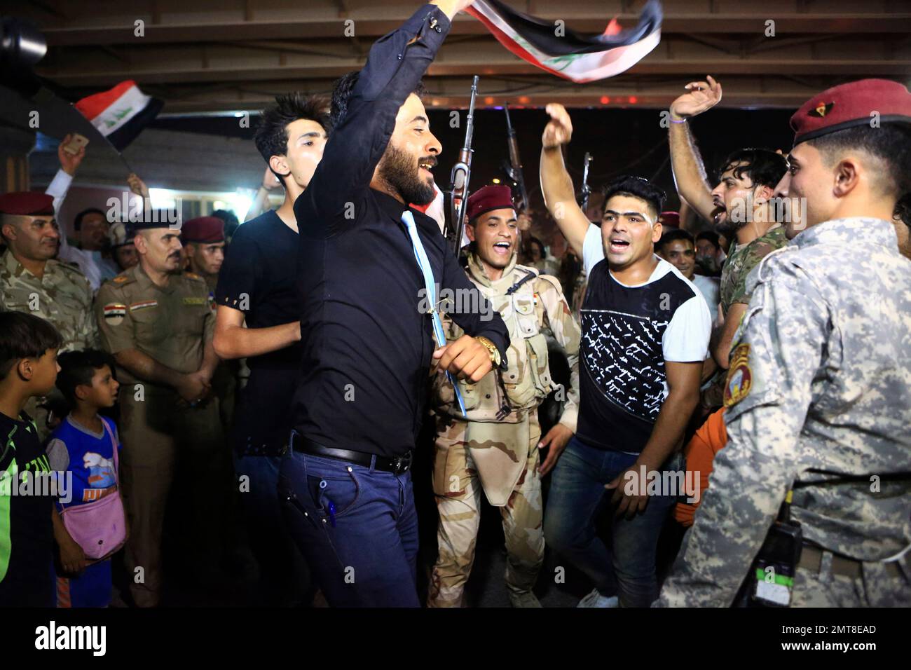 Iraqi security and civilians celebrate while holding national flags, in ...