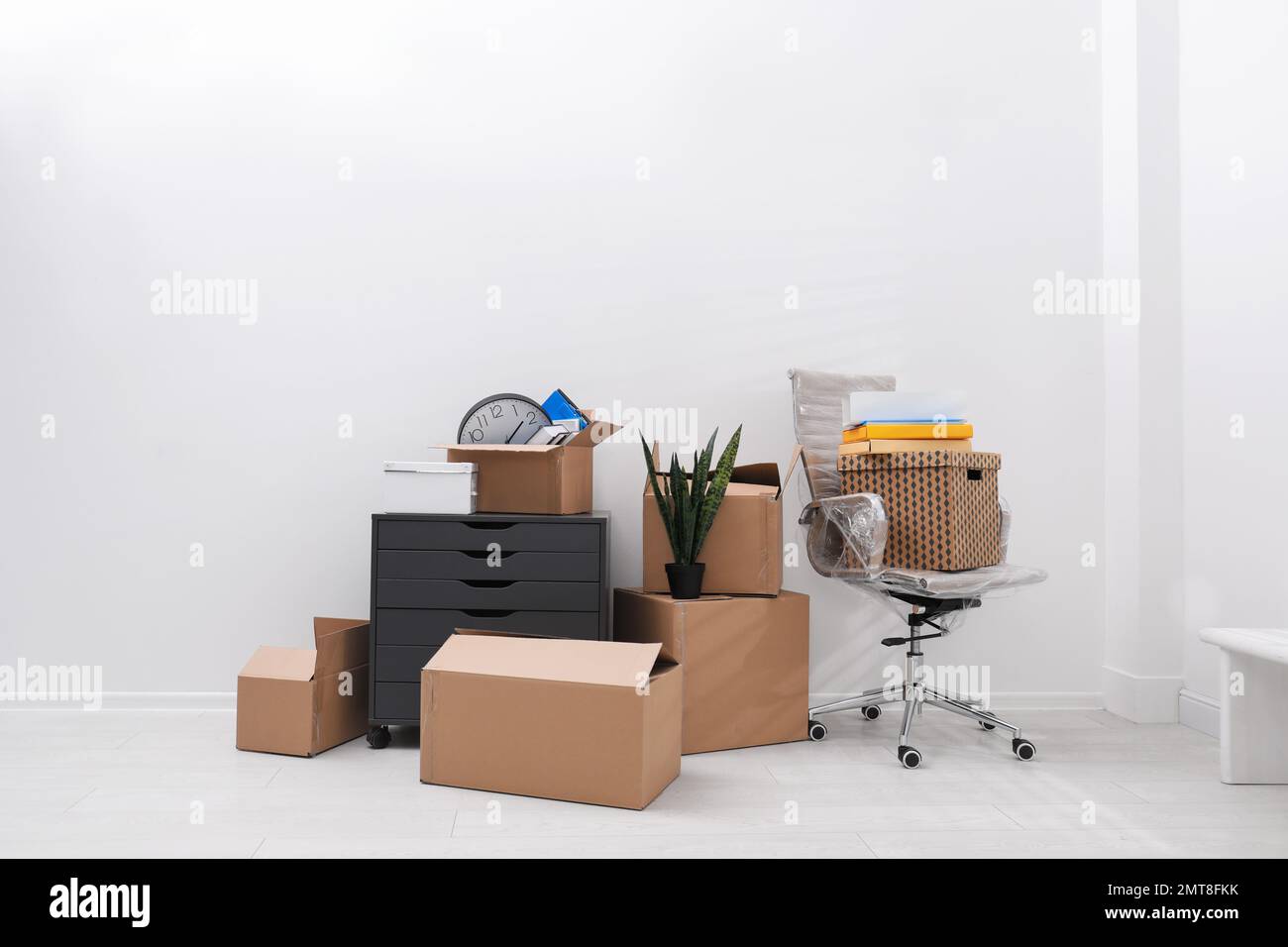 Cardboard boxes and packed belongings near white wall. Moving day Stock ...