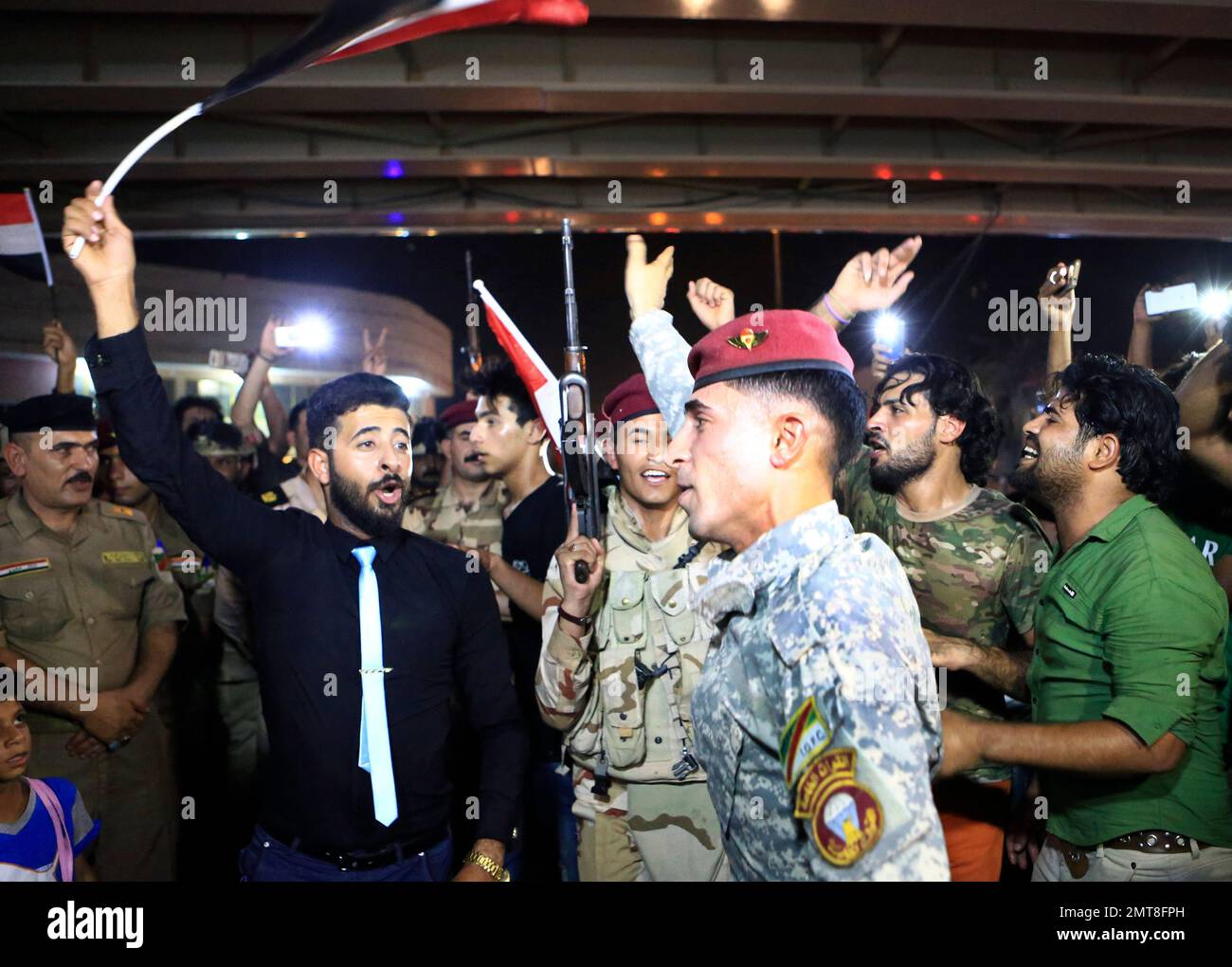 Iraqi security and civilians celebrate while holding national flags, in ...