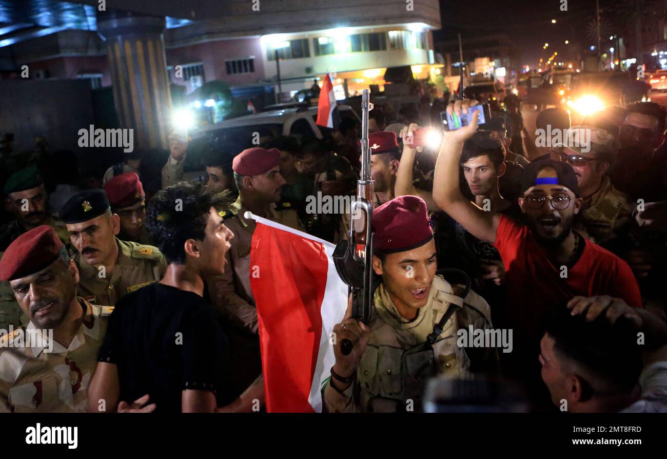 Iraqi security and civilians celebrate while holding national flags, in ...