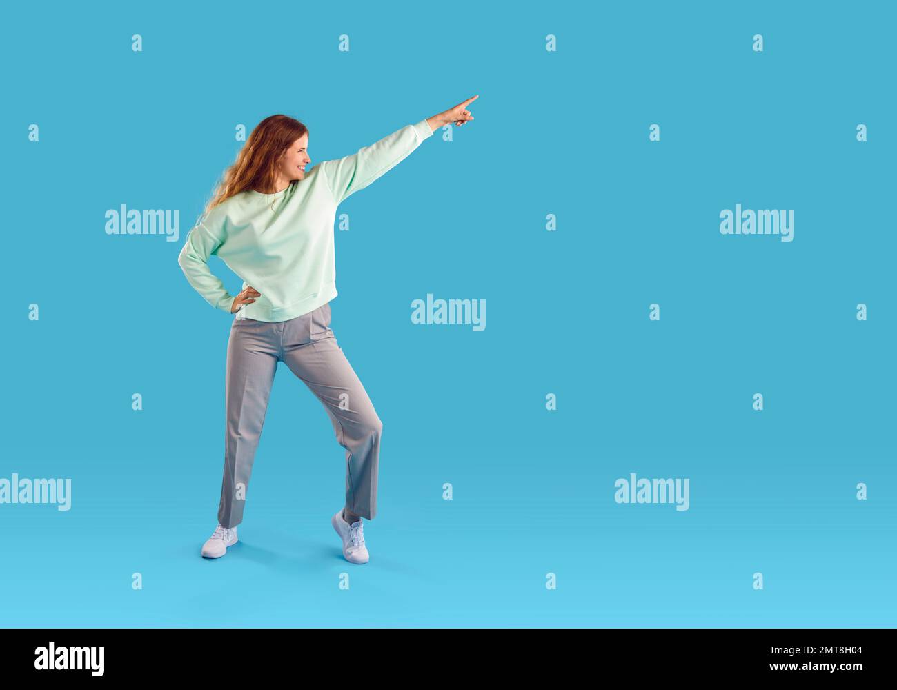 Funny woman in casual outfit dancing and pointing finger to side on ...