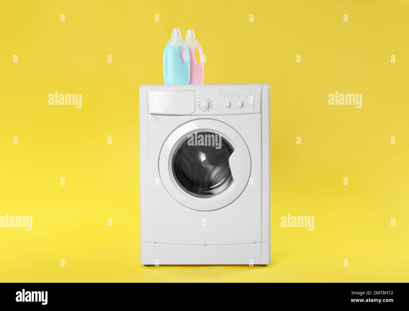 Modern washing machine with detergents on yellow background. Laundry ...