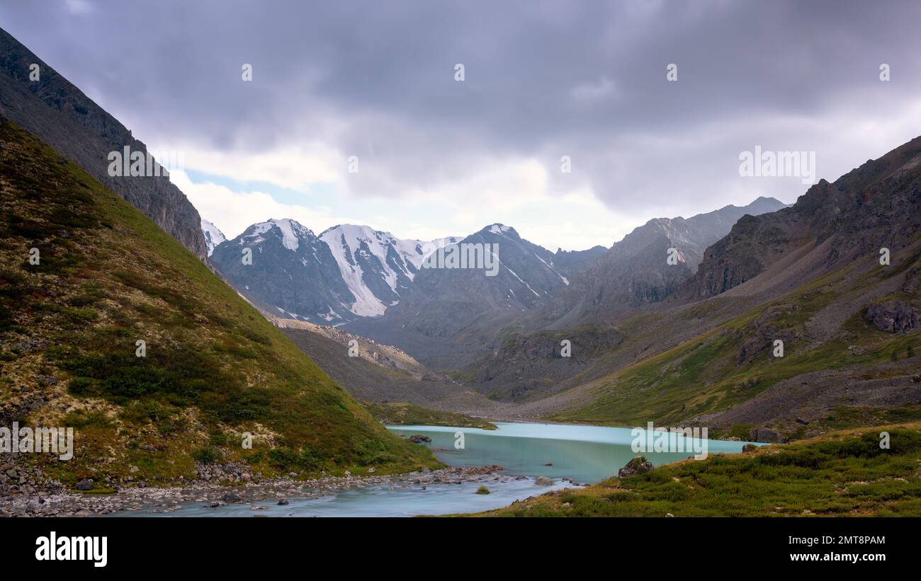 The turquoise water of the Karakabak River flows out of the lake among ...