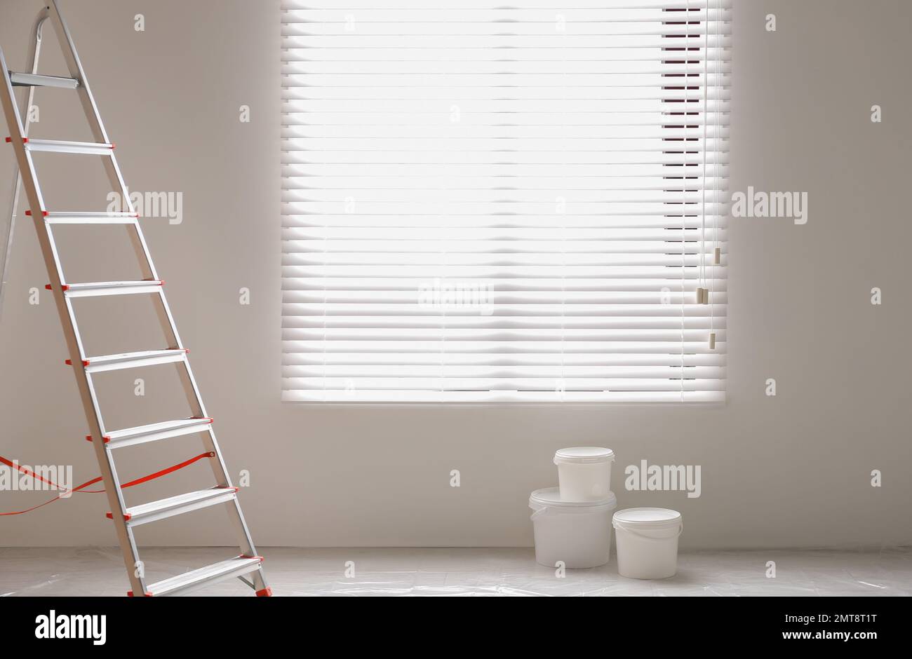 Stepladder and buckets with paint near wall in room. Interior ...