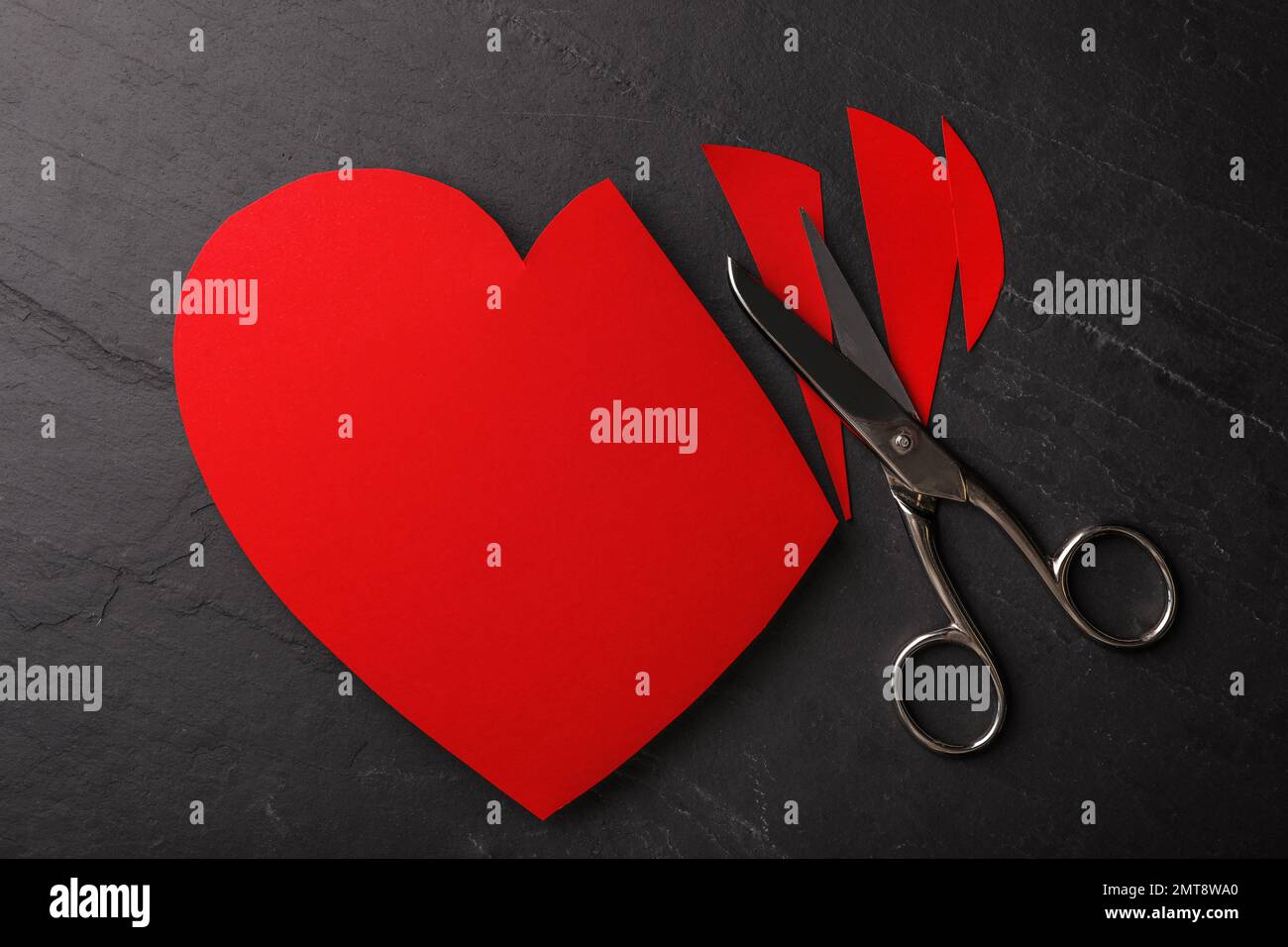 Cut paper heart and scissors on black stone background, flat lay ...