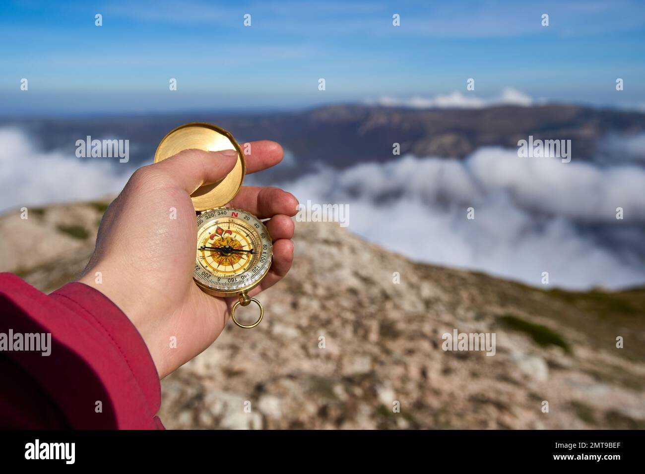 Closeup hand holding compass with mountain and clouds background ...