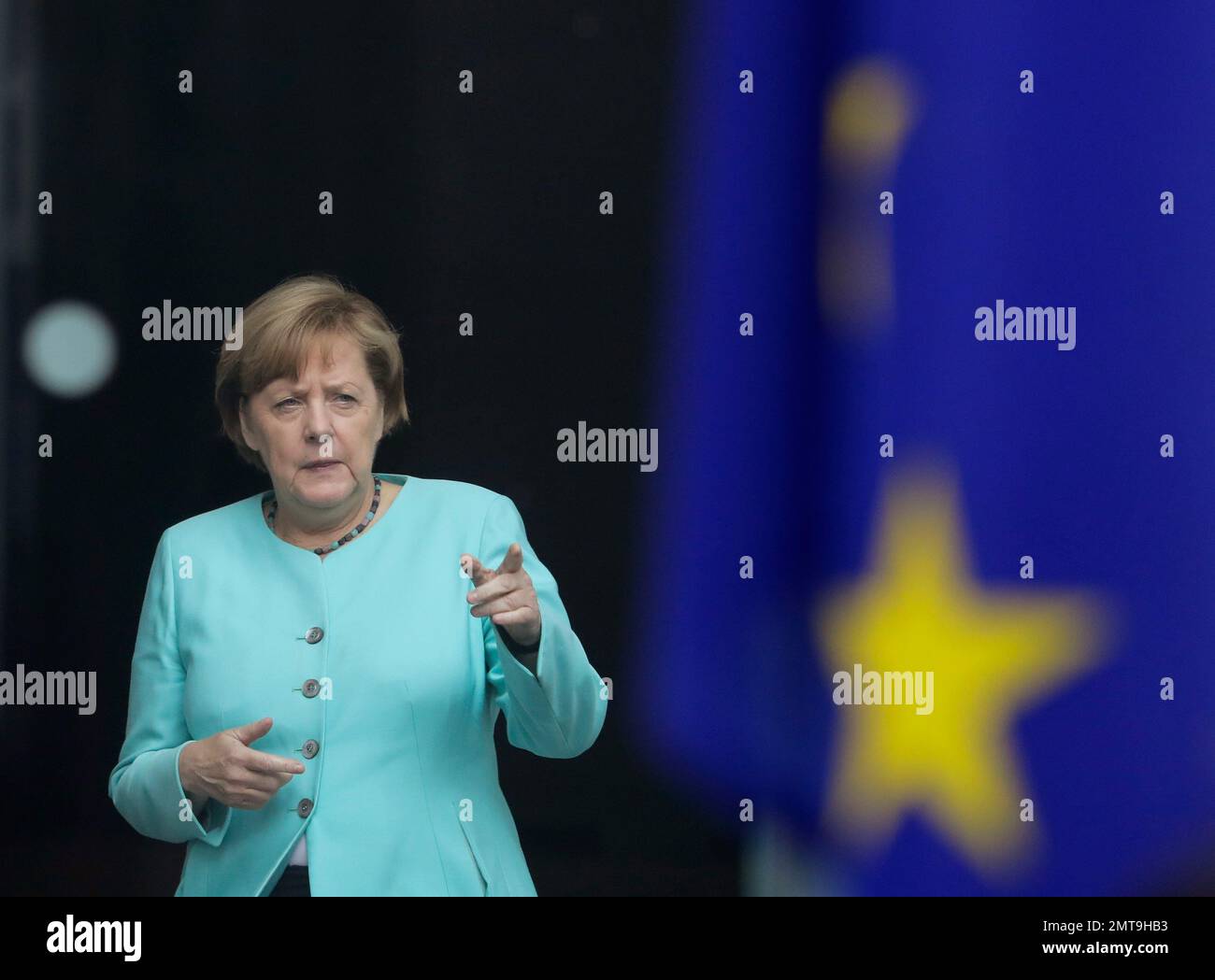 German Chancellor Angela Merkel stands behind a European flag as she ...
