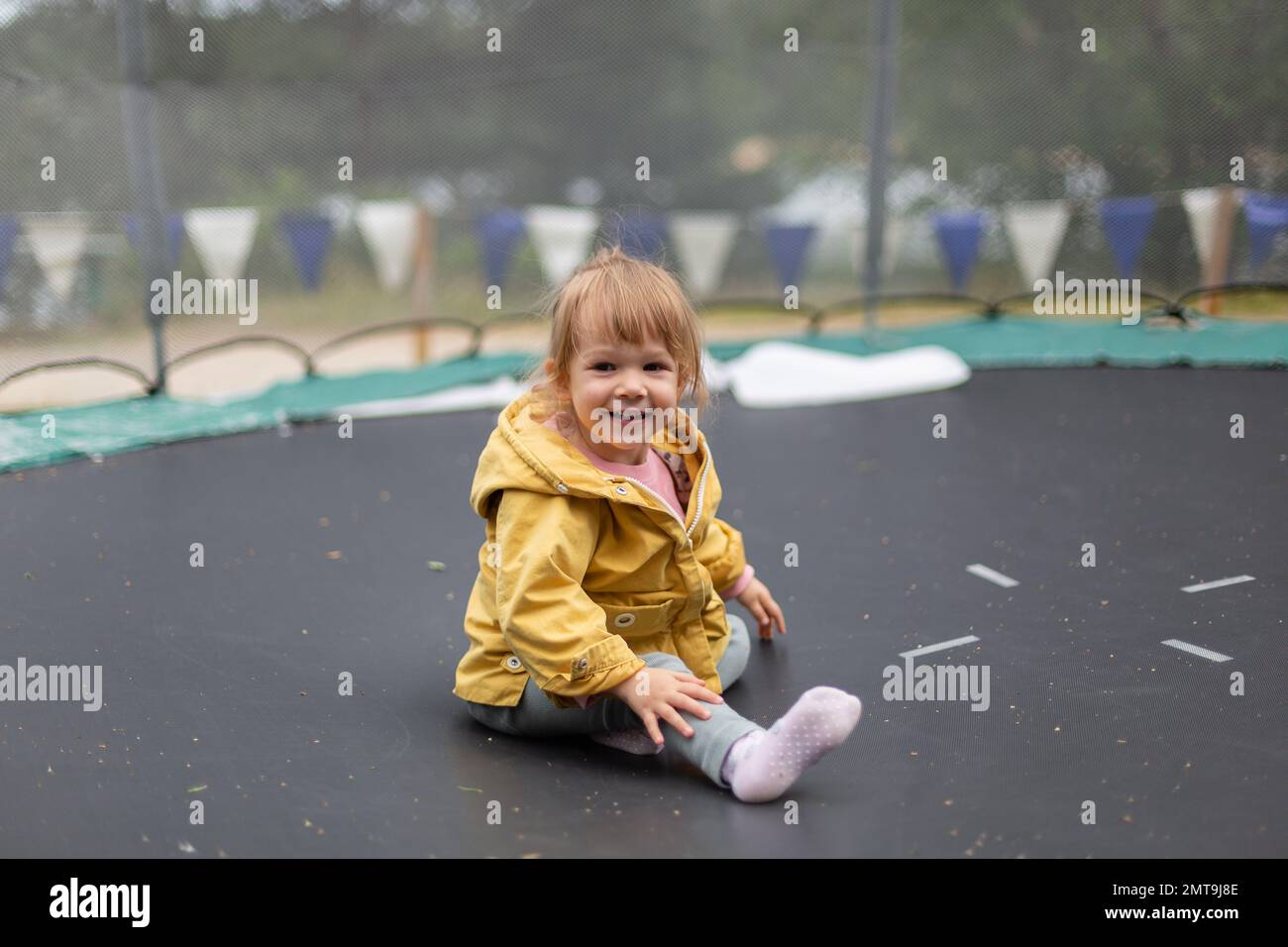 Little girl jumping on trampoline and going down the slide Stock Photo ...