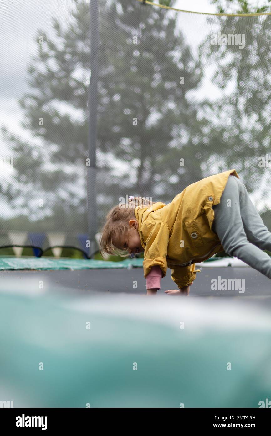 Little girl jumping on trampoline and going down the slide Stock Photo ...