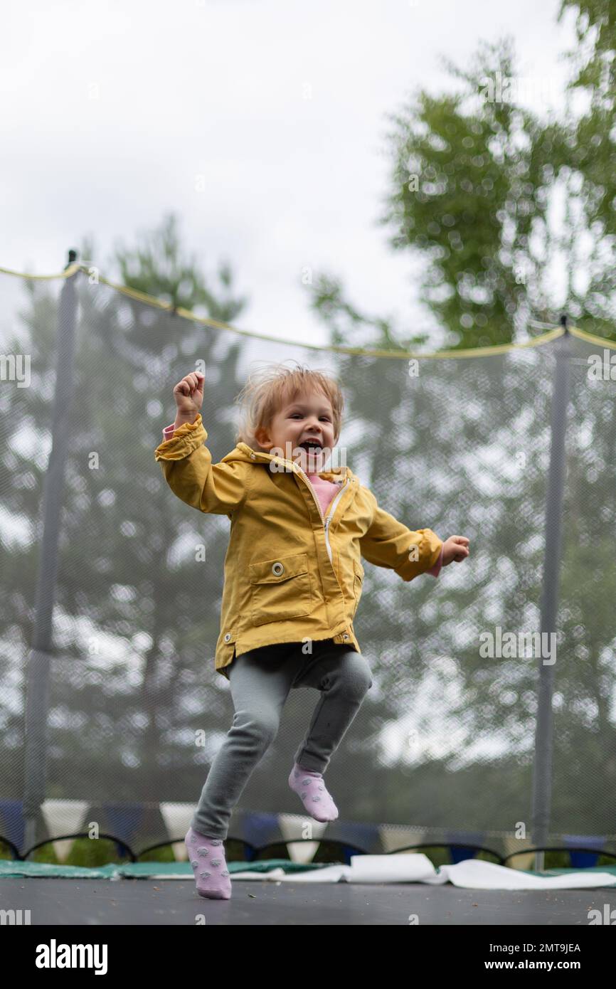 Little girl jumping on trampoline and going down the slide Stock Photo ...