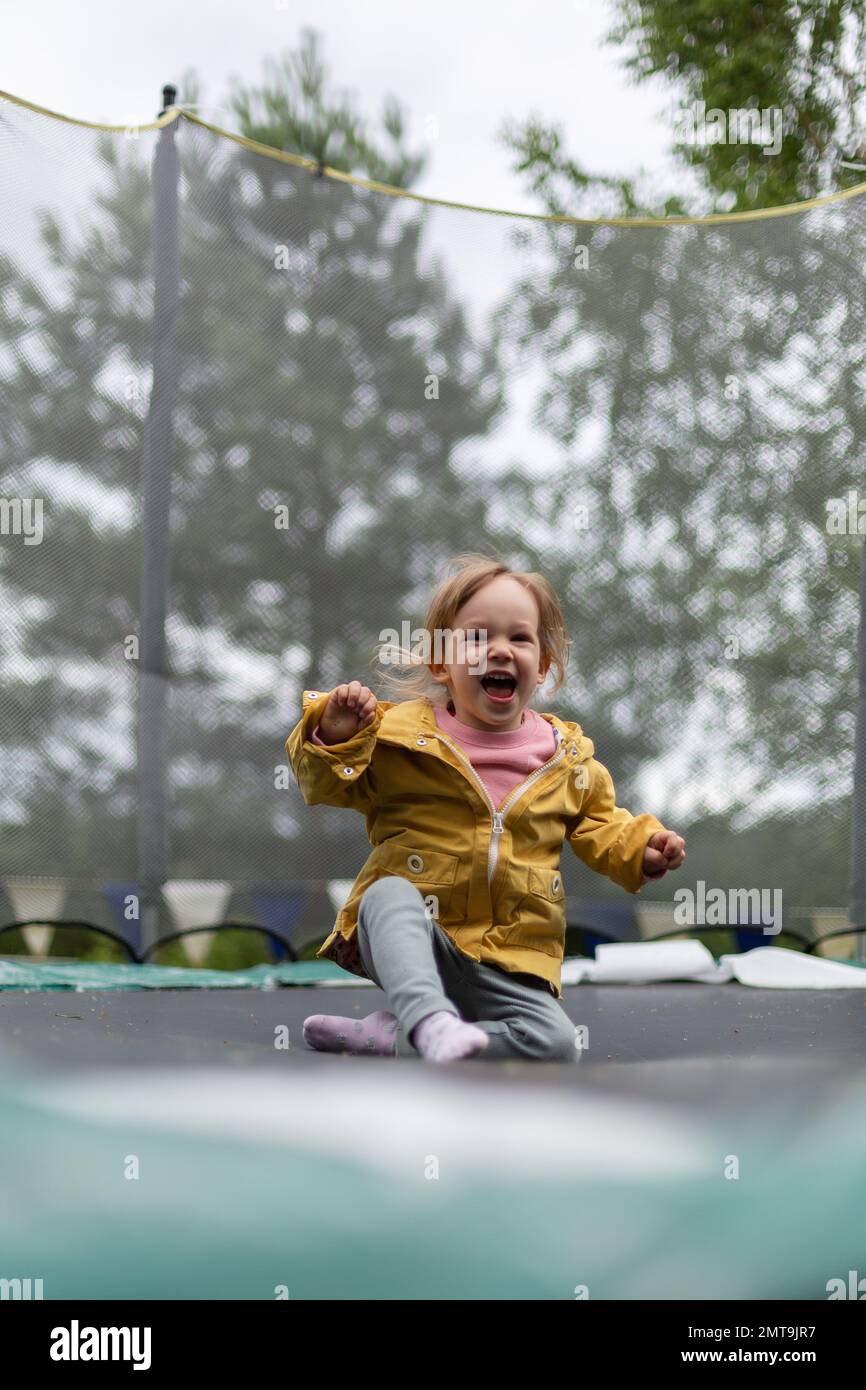 Little girl jumping on trampoline and going down the slide Stock Photo ...
